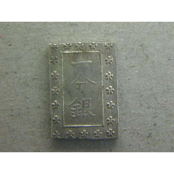 品位　銀８７３／その他１２７　量目８．６３ｇ　天保一分銀と比べますと、切り方が荒く、それが安政一分銀の特徴にもなっています。また、「是」字の第８画と９画が交叉しておらず、人になっています。側面の仕上げは、概して荒いやすり目が入っています。（...