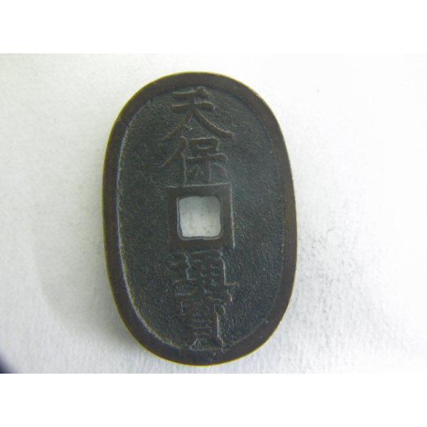 天保通寶は天保６年、金座番場仮吹所にて鋳造が始められ百文通用と定められました。当時この貨幣は小判型であることから、とても人気がありました。各地で鋳造され、手替わりが多くあります。本座の通用銭を用いた手で、輪と郭が銭文より高い。