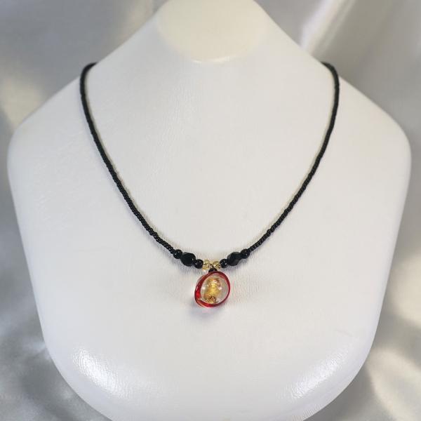 金箔を巻いたビーズを透明のガラスで覆い、赤い筋状のガラスかけてアクセントにした、シックなペンダントネックレスです。カジュアルな服装にも、オシャレをした時にも合いますので、いろいろなシーンでお楽しみいただけます。他とは違う、少し個性的なアクセ...