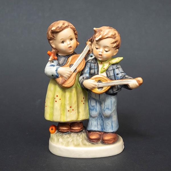 『Happy Days（幸せな日々）』と題されたゲーベルのフンメル人形（陶器人形）。楽器を抱えながら歌う姉弟がモデル。原題は"Hausmusik（ホームコンサート）"なので、家族の前で歌っているのでしょうか？耳を澄ませば歌声が聞こえてきそう...