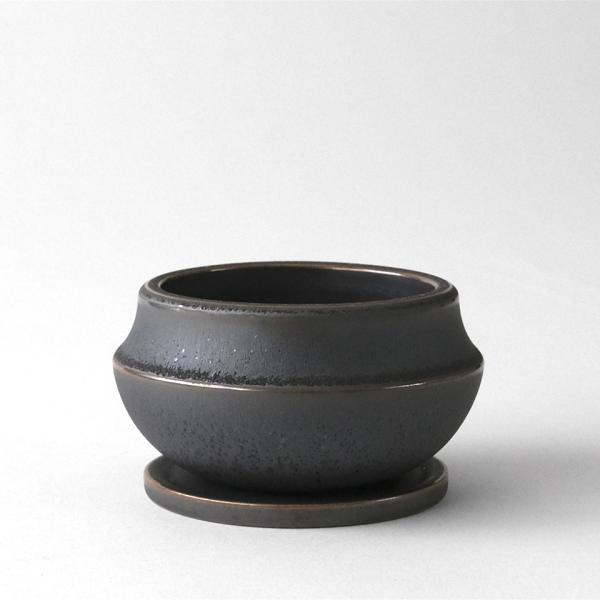金属系成分を含んだ釉薬の使用して製作された植木鉢全体はマットなシルバーブラック角に出るゴールドラインのエッジは艶があり、光の反射でシャープさをより引き立てます。表面はさらりとした感触で、マットな質感素材の特性上、油脂が付着しやすいため経年変...
