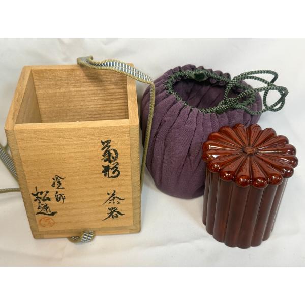 塗師 松通作 菊形茶器です 菊の花弁を模した縦筋の造形が大変美しく 艶やかな漆の風合いが上品です 経年在庫品で状態は非常に良好です 内部は黒塗りで丁寧な仕上げとなっています 紫色の仕覆（しふく）と共箱が付属する本格的な一品です 茶席に季節感...
