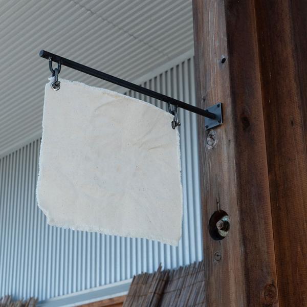 帆布を使ったフラッグ型の看板。外で使うことで風に揺られ爽やかな印象を与えます。帆布を使ったフラッグ型の看板。外で使うことで風に揺られ爽やかな印象を与えます。クロカワと呼ばれる鉄材が作られる過程で自然にできる青黒い被膜がついた状態のまま使用し...