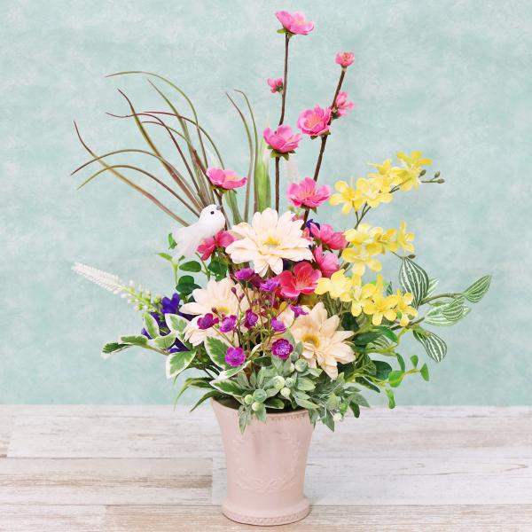 春らしい色合いの花々と白い鳥のピックが印象的なアレンジです。サイズ：約高さ37cm×幅30cm×奥行20cm＊商品の仕様は変更になる場合がございます＊受注制作のため数日お時間をいただく場合がございますシルクフラワーとは、シルクの様な光沢のあ...