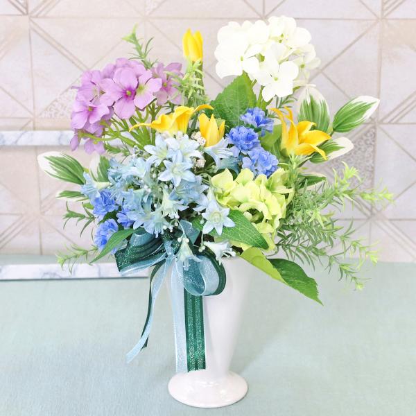 淡いブルーの小花とあじさいのやさしい色合いのアレンジです。サイズ：約高さ32cm×幅28cm×奥行24cm＊商品の仕様は変更になる場合がございます＊受注制作のため数日お時間をいただく場合がございますシルクフラワー(造花)のフラワーアレンジメ...
