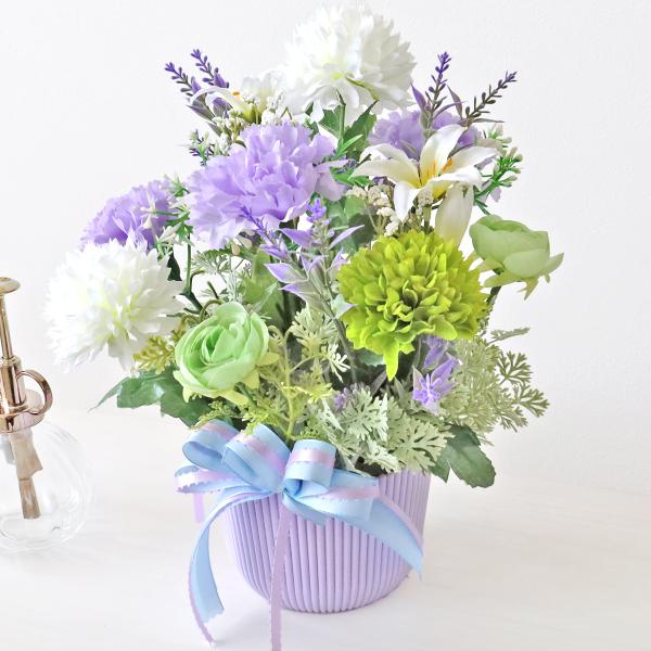 ボールマムやラベンダーの淡いパープルがやさしい印象のアレンジです帰省のお土産に、お盆やお彼岸のご挨拶にどうぞお荷物にならないように直接お届けも承ります。アレンジメントサイズ：約高さ30×幅25×奥行25cmシルクフラワーとは、シルクの様な光...