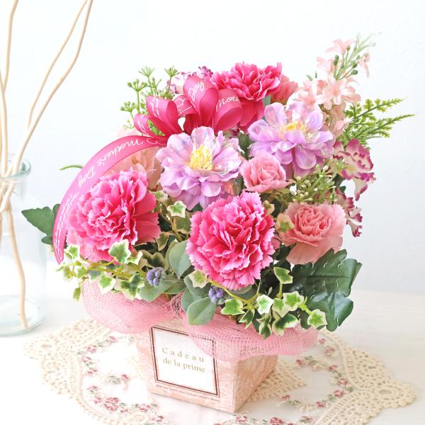 母の日に贈る、ライラックとカーネーションのボックスアレンジメントです。やさしい色合いのペーパーボックスは、軽くて割れないので倒れても安心です。きらめくプリズムフラワーとピンクのカーネーションが、お部屋を明るく彩ります。アレンジメントサイズ：...