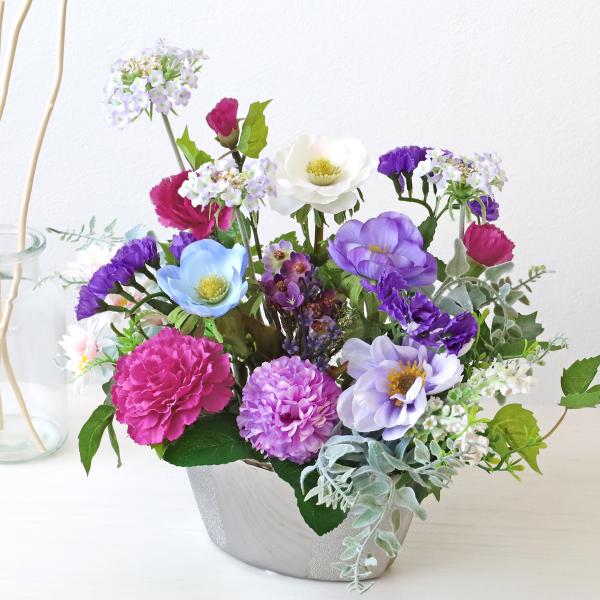 母の日に贈る、アネモネとマムのアレンジメントです。ツヤのある鏡のような花器は、光を取り込むことで美しく輝き、高級感があります。まるで水面に浮かぶように色とりどりの花々が咲くアレンジは、幻想的な空間を演出します。アレンジメントサイズ：約高さ2...