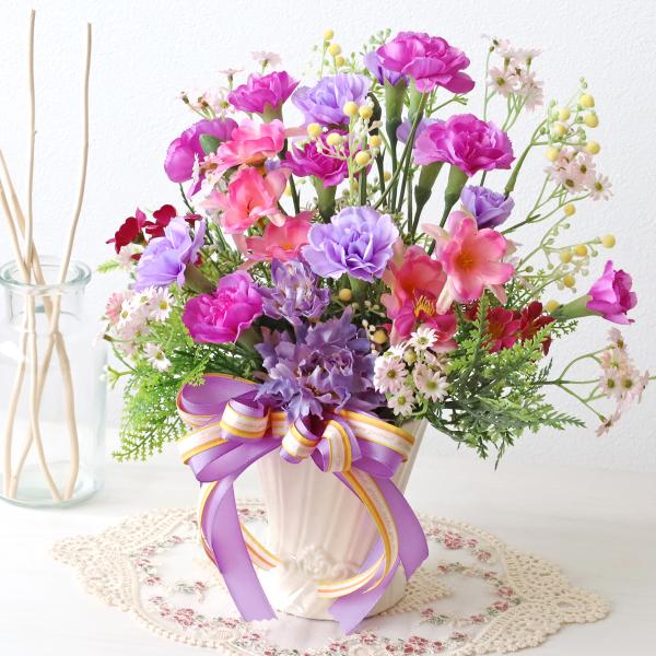 母の日に贈る、ミニカーネーションとおだまきのパープルカラーのアレンジメントです。クラシカルなホワイトの器は、やさしいパープルカラーを引き立たせます。繊細な小花を添えたフェミニンなアレンジは、お母さんへの贈り物にぴったりです。アレンジメントサ...