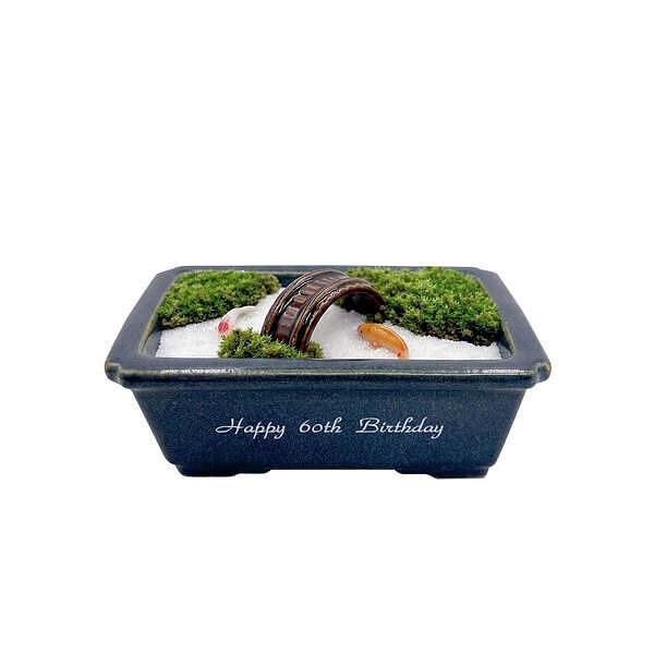 自宅で手軽に日本の美を。なまこ釉の鉢にスナゴケや砂、陶器の小物を配し、自分だけの「枯山水」を作れるキットです。乾燥に強いスナゴケは、水をかけるとパッと葉を開く生命力の変化も楽しめます。鉢の側面にご希望のメッセージが入ります。サイズ : 約 ...