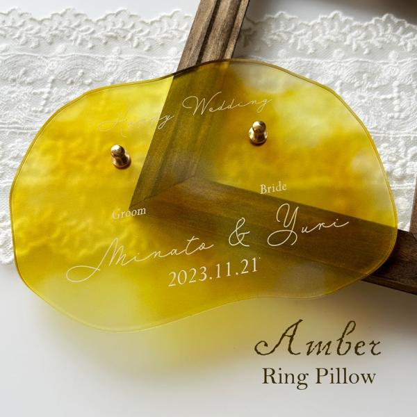 琥珀をイメージしたAmberデザインのアクリル製のリングピローです。アンバー色のリングピローは立てかけスタンドも付いているのでお式が終わってもリング掛けにお使いください。タイトルの変更も可能なのでプレゼントやアニバーサリーグッズにも使えます...