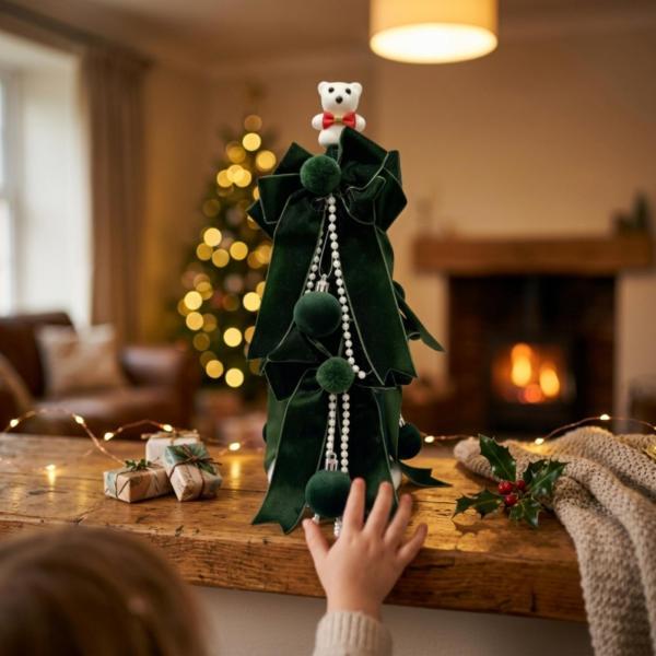 【デザイン】: 重なり合うリボンをデザイン要素にしたユニークなシルエットが特徴のクリスマスツリー置物です。【素材】: 触り心地の良い柔らかなベルベット調の生地を使用し、温かみのある上品な卓上装飾を演出します。【装飾】: 揺れるパール風のビー...