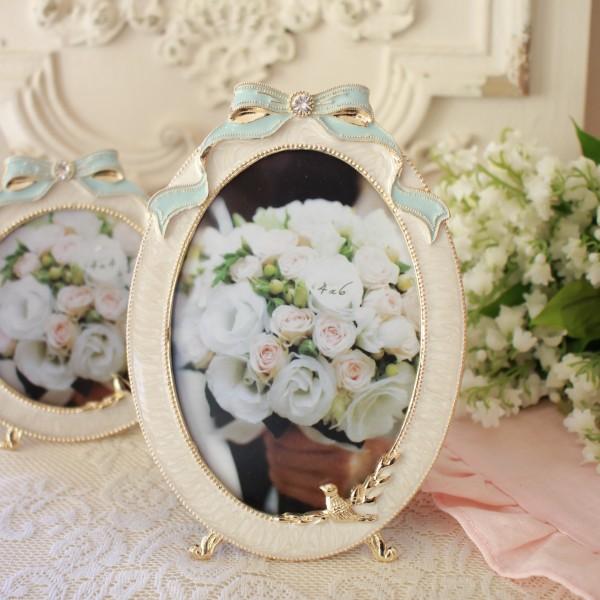 [商品説明]ホワイトのエナメルにブルーリボンが映えるフォトフレームこちらはオーバル型となりますリボンの中央には大きなラインストーン、フレームのふちに小鳥がさえずり、お部屋を可愛く演出します飾りやすいサイズのフォトフレームは、お洒落な贈り物に...