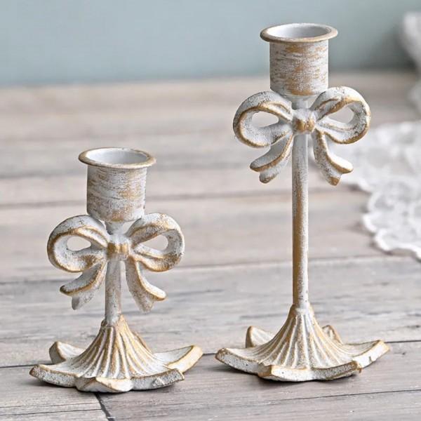 [商品説明]シャビーシックなホワイトカラーのおしゃれなリボンモチーフのテーパーキャンドルホルダートール＆ショート、２サイズセットです華奢なフォルムにお花のようなベースがかわいらしいデザインの燭台ですアンティーク家具やシャビーシックなインテリ...