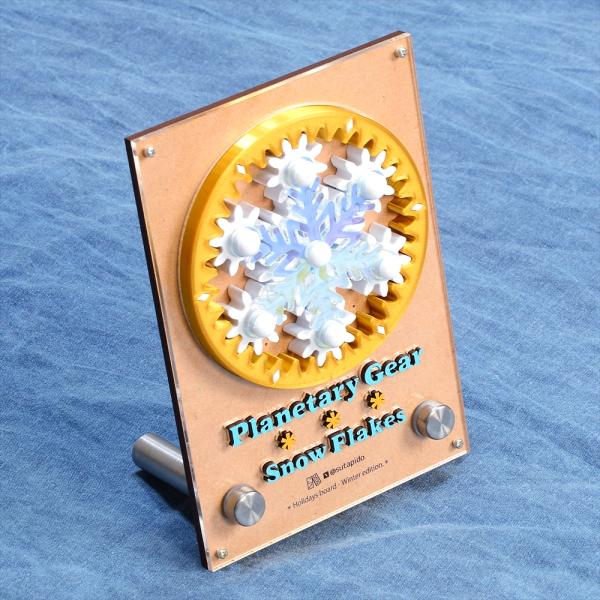 HolidaysBoard-SnowFlakes（ホリデイズボード）スタピ堂オリジナルデザイン中心のギア群がモーターにより、ゆっくり回転します。大きさ縦:約143mm×横:約100mm×厚さ(台座含む):約60mm使用電池:CR2032（試...