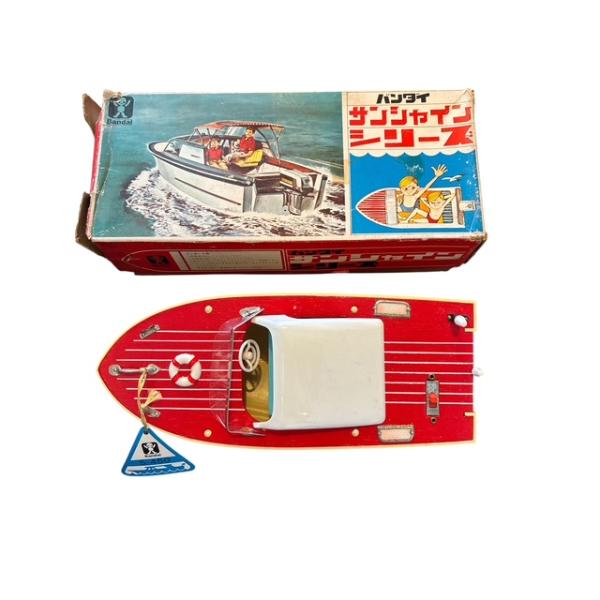 バンダイのサンシャインシリーズ。プラスチック製のスケールモデルモーターボートです。赤色の木製板（デッキ）は白いストライプ模様、前部にはウキワ、中央には白いカバーが付いています。水に浮かべ、スイッチを入れると進む仕組みです。1970年代の模型...
