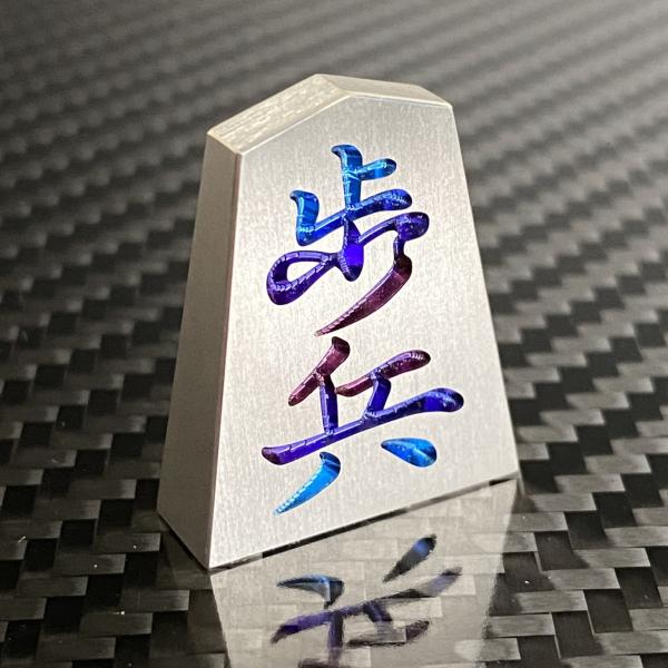 当店オリジナルです。製品重量：約12ｇサイズ：約Ｗ22mm×Ｈ27mm×Ｄ7mm材質：純チタン(TP340）色：本商品はバフによる磨き処理のみで、メッキや塗装は施していません。文字の色は、青〜紫のグラデーションを陽極酸化という方法で入れてお...