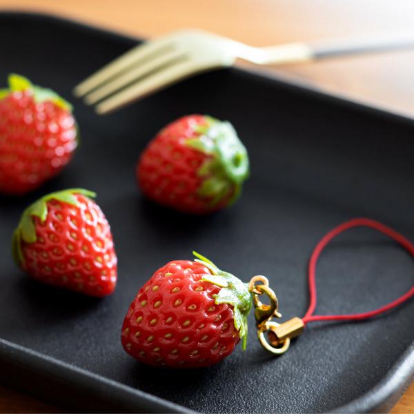 食品サンプルでできた本物と見間違うような苺（いちご・イチゴ）がキーホルダーになりました。携帯・スマホのストラップやファスナーチャームに、苺好きがうなる仕上がりです。ちょっとした撮影用の小物としても活躍します。 苺（いちご・イチゴ）のヘタ部分...