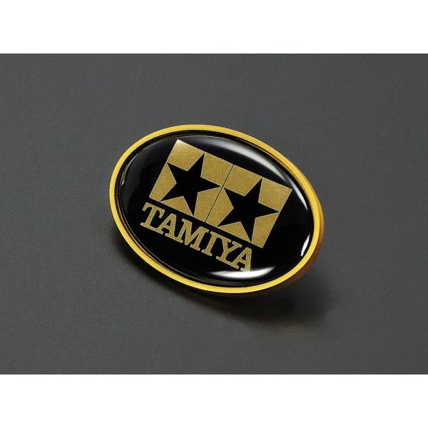 約35ｍｍの亜鉛合金の楕円形の台座に、シリコンエポキシ樹脂でコーティングされた黒地に金色のタミヤマークをあしらったピンバッジです。裏面には、バタフライクラッチが付きますので、バッグや帽子、服に付けてブローチの様にご利用いただけます。【 基本...