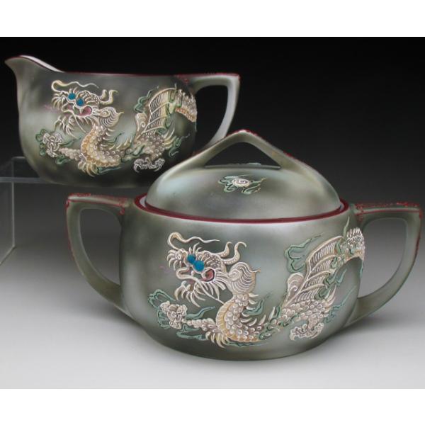 『オールドノリタケ ドラゴン盛り上げ シュガー＆ミルクポット』一陳(泥漿)盛り上げ。威風堂々の言葉がお似合いなドラゴン。極めて緻密に装飾され、鱗や翼などの質感には魅了させられる。背後に暈しで濃淡つけた灰緑。ドラゴン登場に相応しく、重厚な空気...