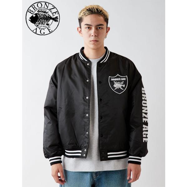 BRONZE AGEのスタジアムジャンパー。オーバーサイズデザインのためビッグシルエットの着こなしが楽しめます。ブランドアイコンであるスカルフィッシュのロゴをパイレーツ風にデザイン。左胸とバックに大胆にプリントした一枚。袖にもブランドロゴを...