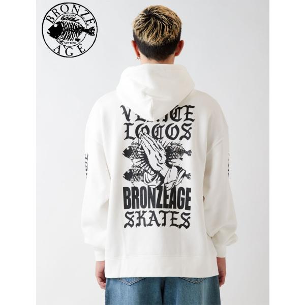 BRONZE AGEの裏起毛パーカー。オーバーサイズデザインのためビッグシルエットの着こなしが楽しめます。チカーノファッションならではのプレイングハンズにスカルフィッシュを組み合わせ、ロックステディクルーフォントをデカプリント！インパクト抜...