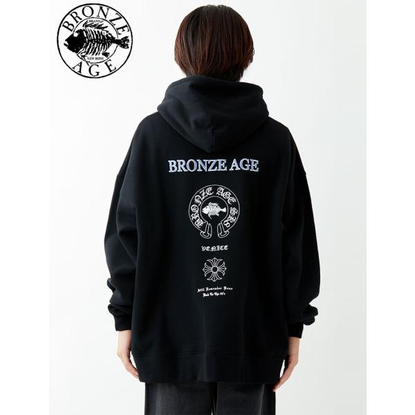 BRONZE AGEの裏起毛パーカー。ビッグシルエットです。ブランドアイコンであるスカルフィッシュのサークルロゴやブランドロゴ、クロスモチーフを刺繍した一枚。一枚で存在感を出して着こなすことができます。肌触りの良い柔らかな裏起毛素材なので、...