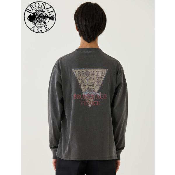 BRONZE AGEのロングスリーブTシャツ。レギュラーシルエットです。フロント左胸とバックに定番のトライアングルロゴを配置。ボディには製品ピグメント加工を施し、プリントはクラックプリントで表現。古着アイテムの風合いを演出します。ユニセック...