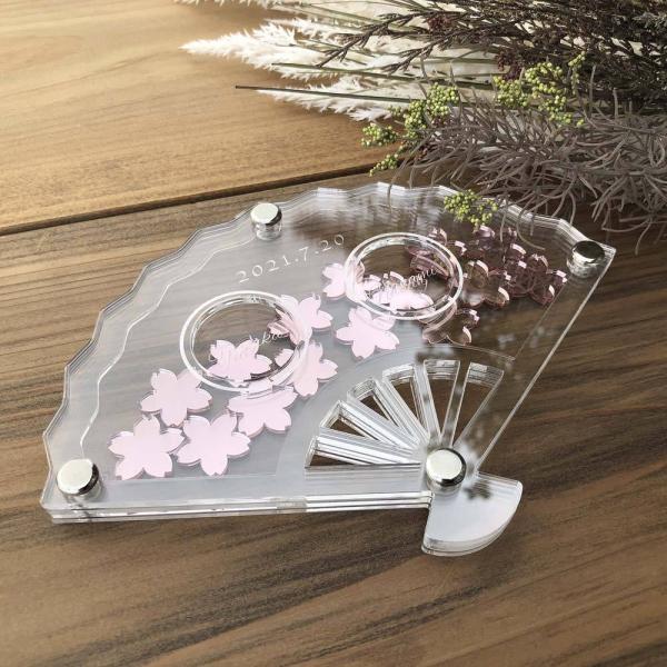 綺麗なミラーアクリルの桜が扇子の中に入ったリングピローです。上品なデザインは和婚など結婚式の演出におすすめです。 また、縁起のいい扇子の形は結婚のお祝いギフトとしてもぜひおすすめです。リングピローには新郎新婦様のお名前と挙式日を彫刻でお入れ...