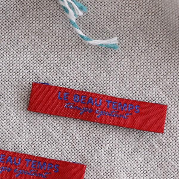 5枚の価格です。当店オリジナルの刺繍タグです。ハンドメイド作品のワンポイントにお使いください。両端は折り曲げ加工をしておりますので、そのまま四方を糸で縫い付けてご利用ください。カラー：地色[ 赤 ]×文字色[ 青 ]素　材：ポリエステルサイ...