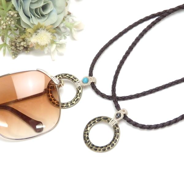 アンティークゴールドカラーのリングのバチカンをマクラメコードで作成し、そこに天然石をあしらったおしゃれかっこいいメガネホルダーできました。メガネを外した時にひっかけておく眼鏡ホルダーネックレスです。サングラスや老眼鏡、メガネをおしゃれにドレ...