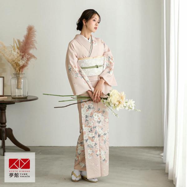 くすみ系ピンクに優雅な野ばらが咲き誇る訪問着。サーモンピンクの地色に、やさしく流れる流水文様と、白や薄紅色の野ばらが舞うように描かれた一着。肩から袖、裾へと流れるような柄付けが、まるで風にたなびくような軽やかさを演出し、立ち姿まで美しく見せ...