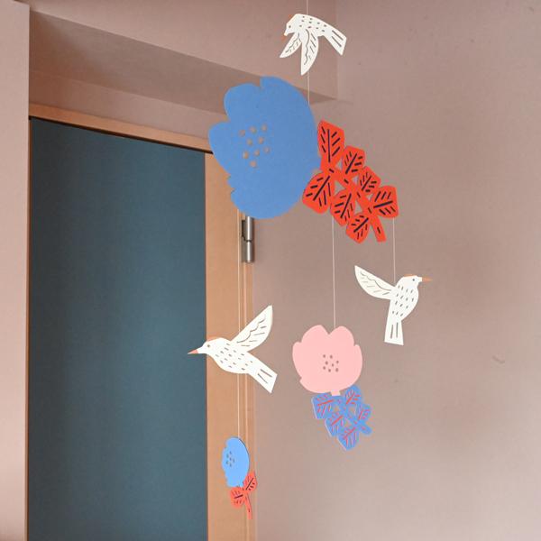 鮮やかな色彩の花の周りを３羽のハチドリが舞うーーそんな自然の情景を切り取ったような美しいモビールです。見た目も精緻なこのモビールは、カットされた紙を手作業で一枚ずつ貼って作られています。ハチドリの羽は立体になり、わずかな空気の流れをとらえて...