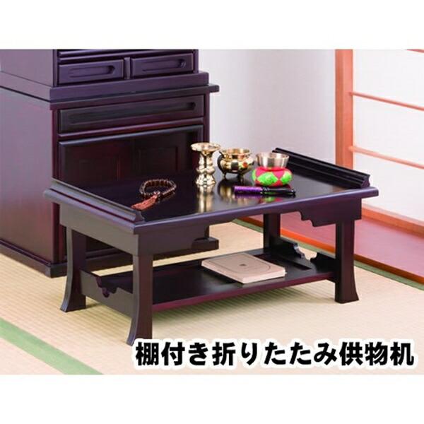 お仏壇になじむ色みの便利な折りたたみ供物机。●お供え物置きや法要時の焼香卓、文机に。桐製で軽く、持ち運びや収納もラクラク。●棚板は取り外し可能。●折りたたみ式でスッキリ収納。商品名：棚付き折りたたみ供物机カラー：黒檀調/紫檀調サイズ／使用時...